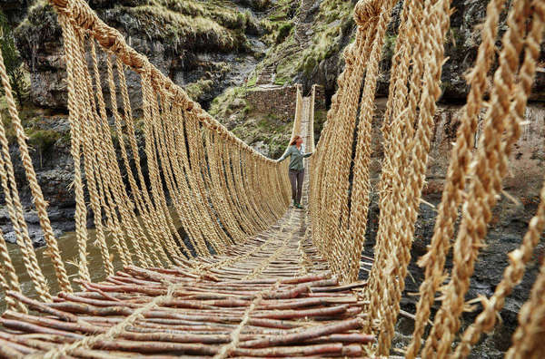 Female tourist crossing Inca rope bridge, Huinchiri, Cusco, Peru ...