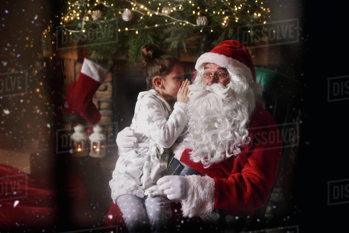 Young girl sitting with Santa, whispering into Santa's ear - Royalty ...