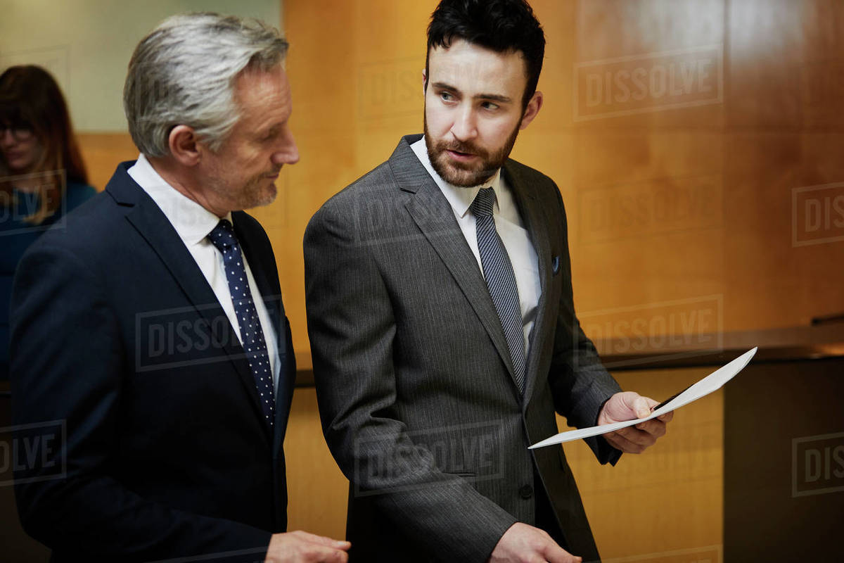 Two businessmen looking at paperwork in reception - Royalty-free Stock ...