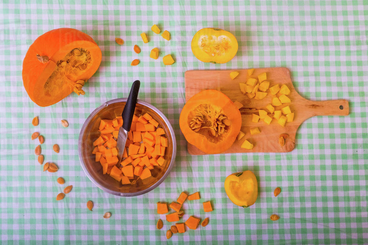 Pumpkin cut into pieces on chopping board with bowl full of cubed ...