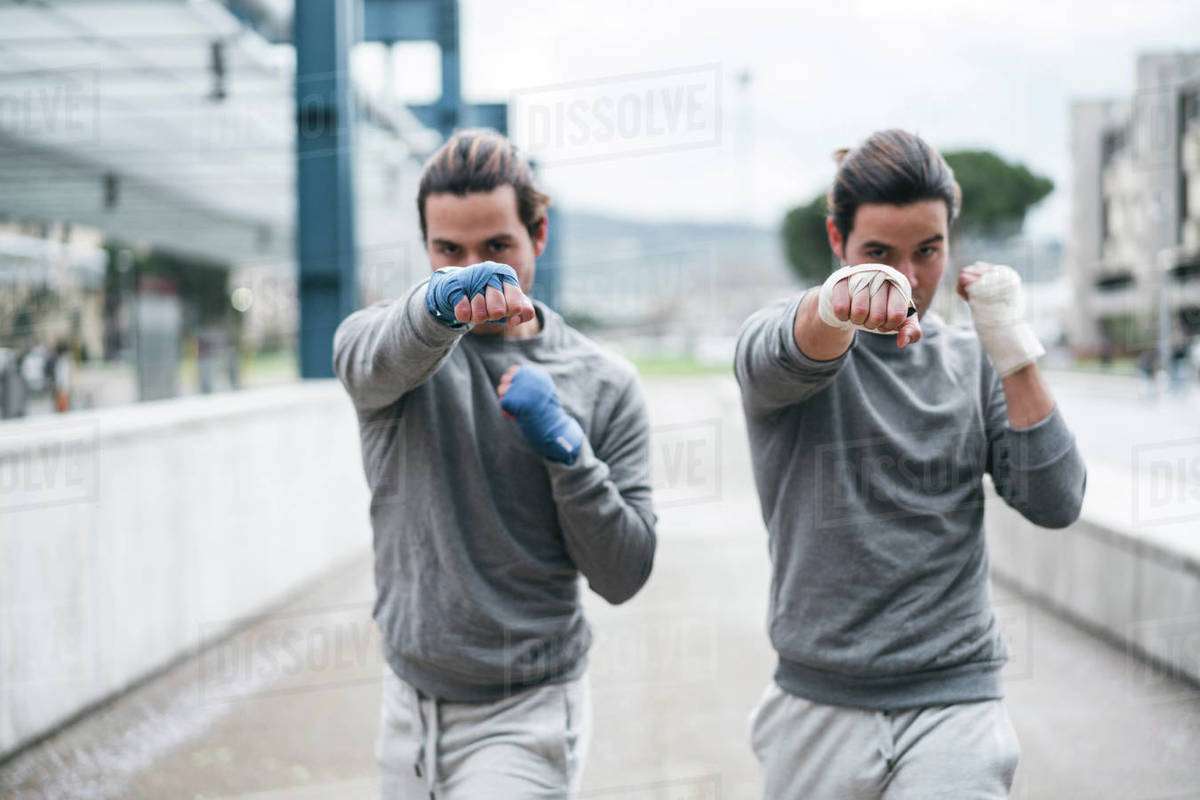 Identical male adult twin boxers training outdoors, fighting stance ...