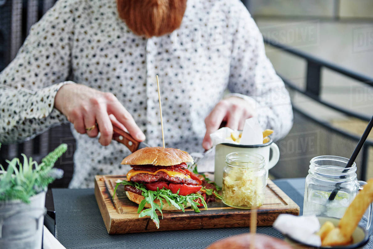 Bearded man eating burger, cropped - Royalty-free Stock Photo | Dissolve