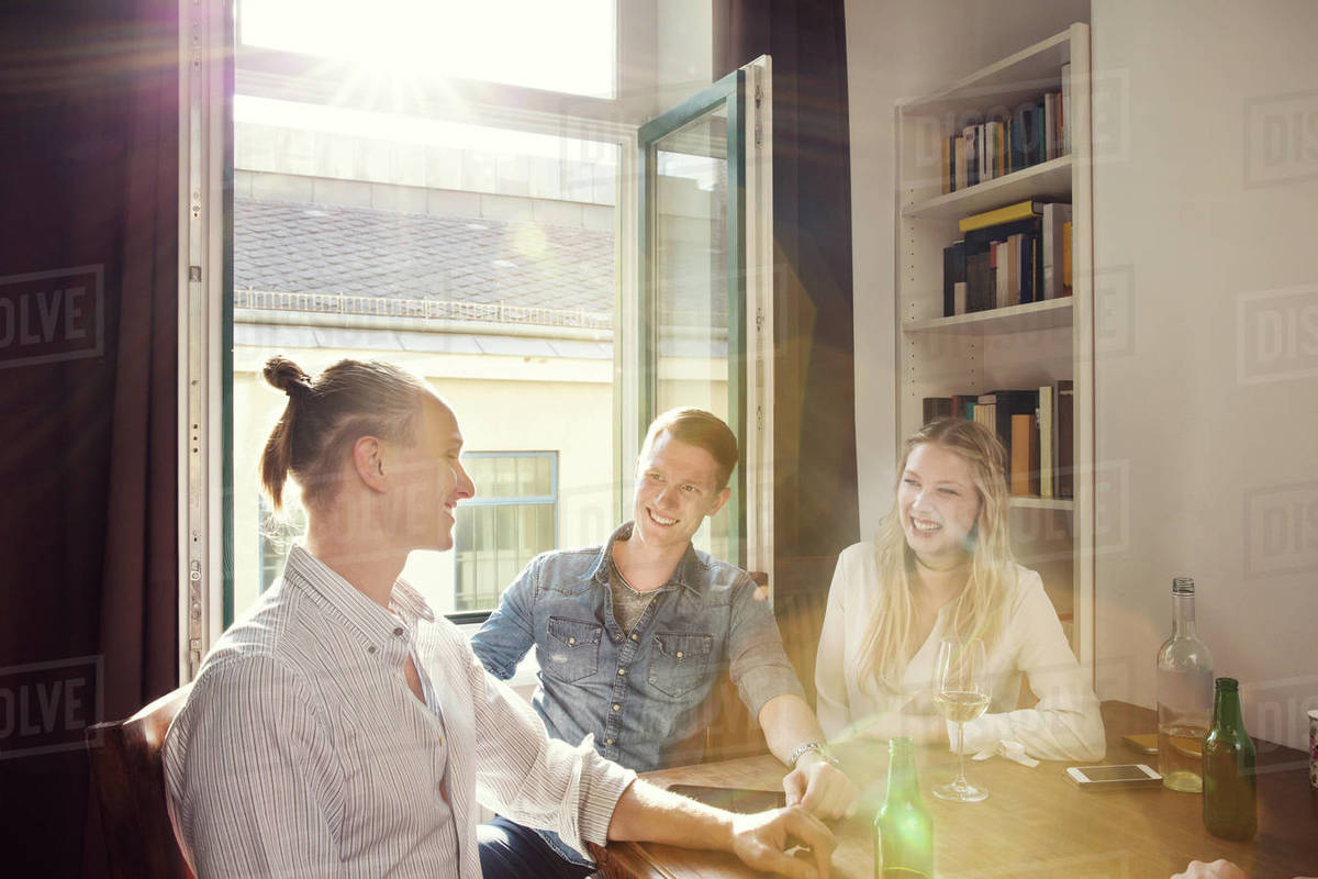 Group of friends chatting over drinks at home - Stock Photo - Dissolve