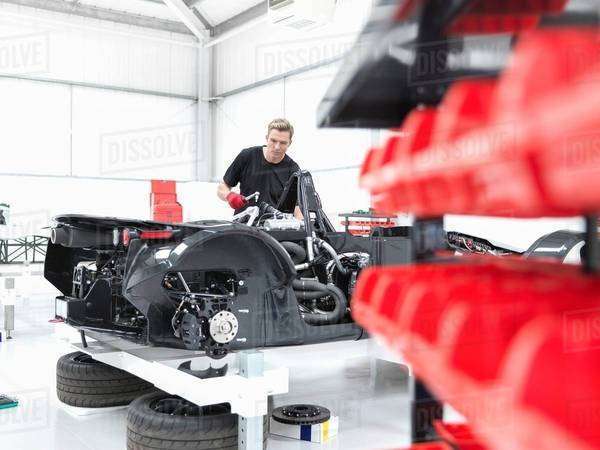Engineer assembling supercar in sports car factory - Stock Photo - Dissolve
