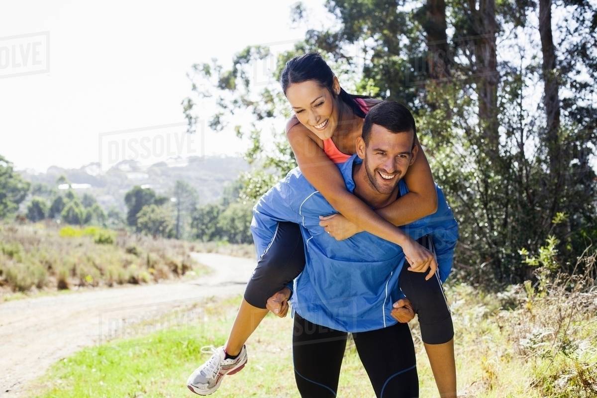 Female jogger riding piggyback on man - Royalty-free Stock Photo | Dissolve