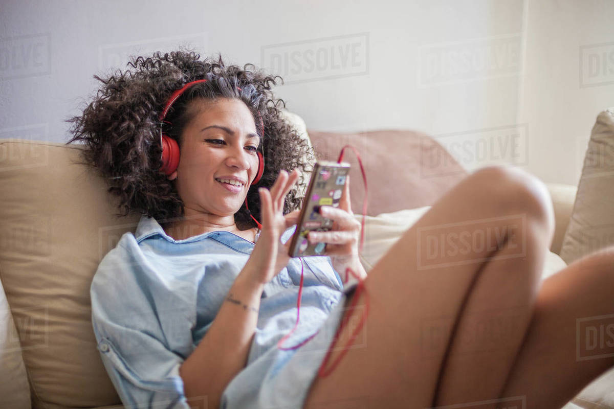 Woman listening to music on mobile phone at home - Royalty-free Stock ...