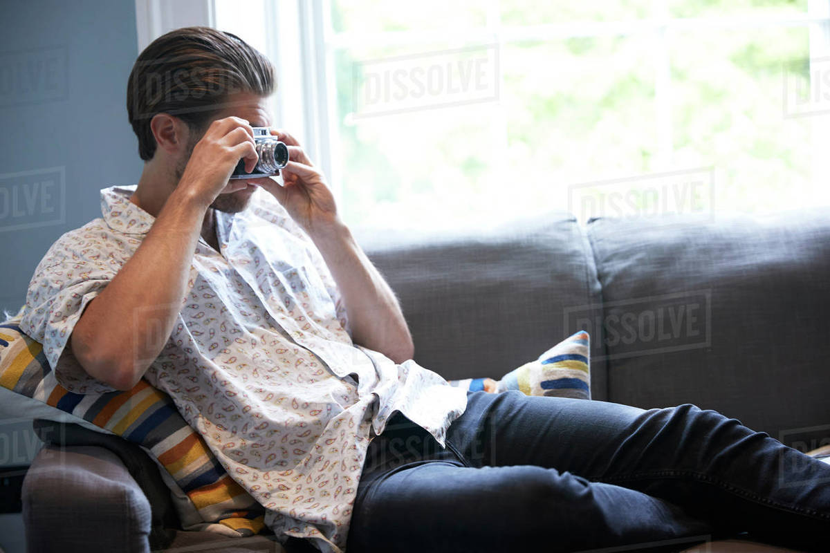 Man using camera on sofa - Royalty-free Stock Photo | Dissolve