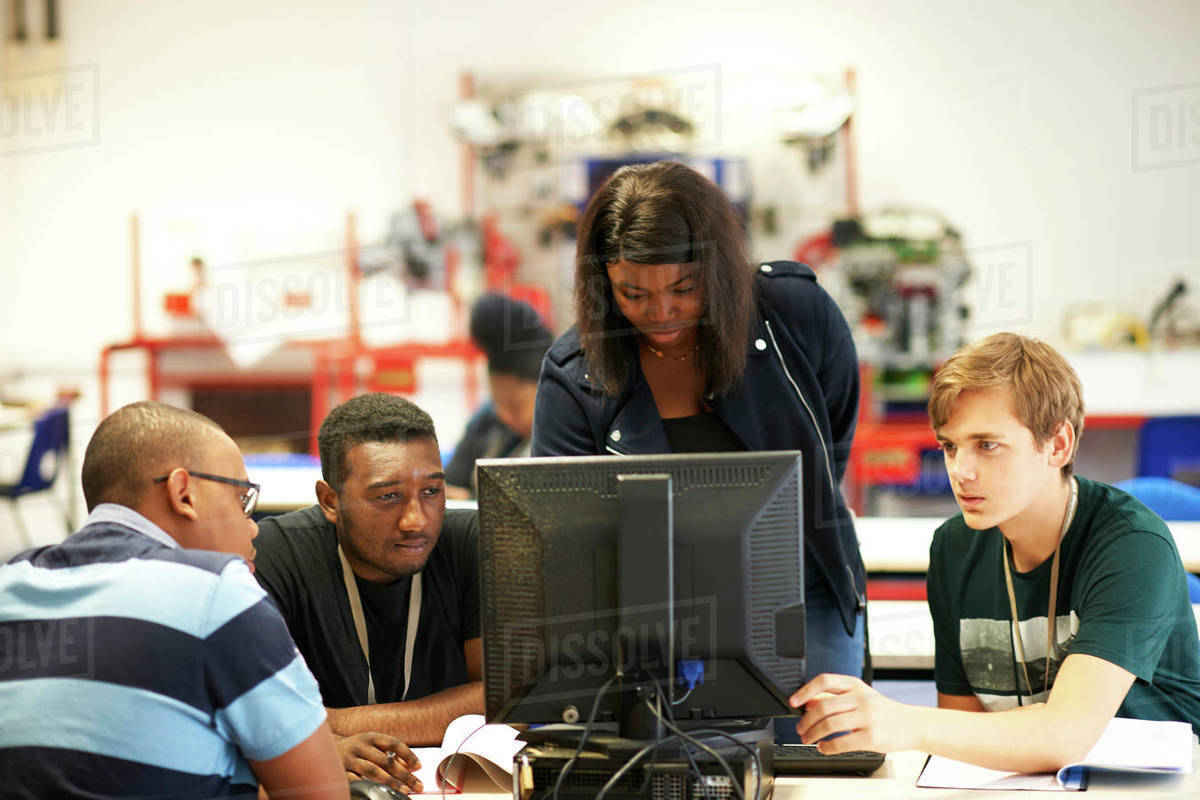 Male and female higher education students looking at computer in ...