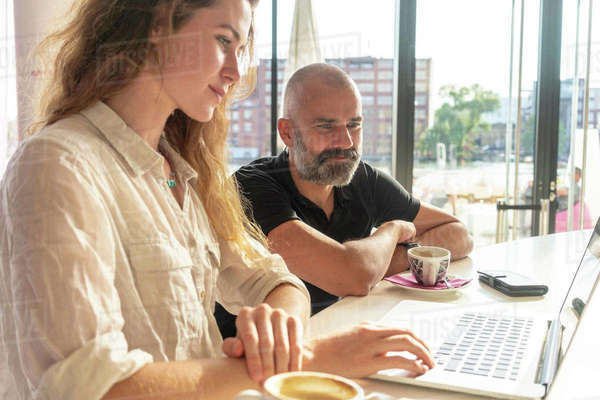 Two entrepreneurs using laptop and having coffee in office - Stock ...