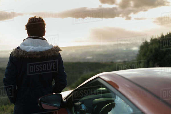 Man resting against car on roadside, enjoying view on hilltop - Royalty ...