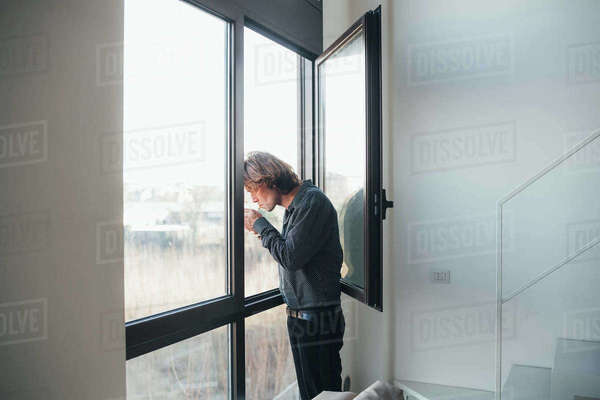Businessman smoking out of window - Stock Photo - Dissolve
