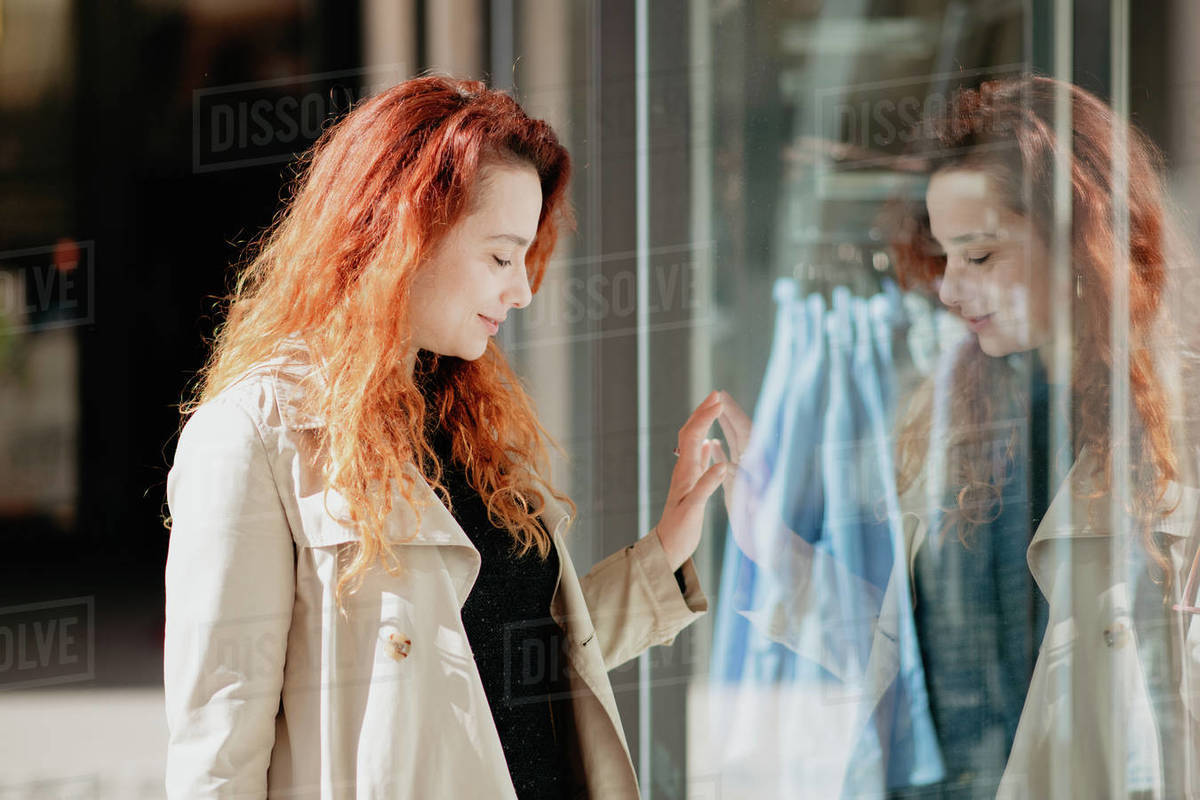 Woman looking into window of fashion boutique - Stock Photo - Dissolve