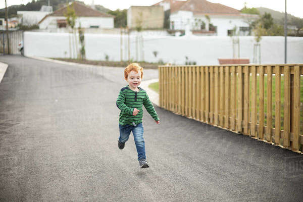 Boy running on road in residential area - Stock Photo - Dissolve