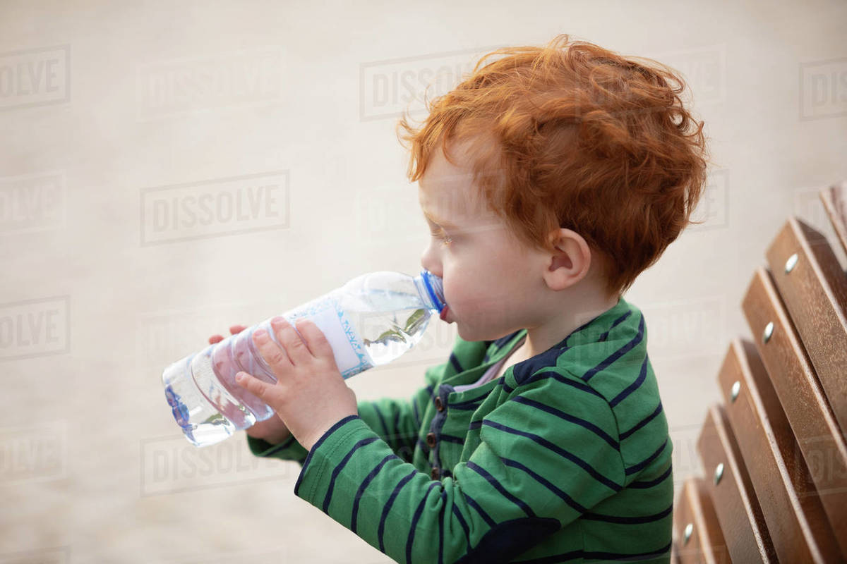 Boy drinking water on park bench - Royalty-free Stock Photo | Dissolve