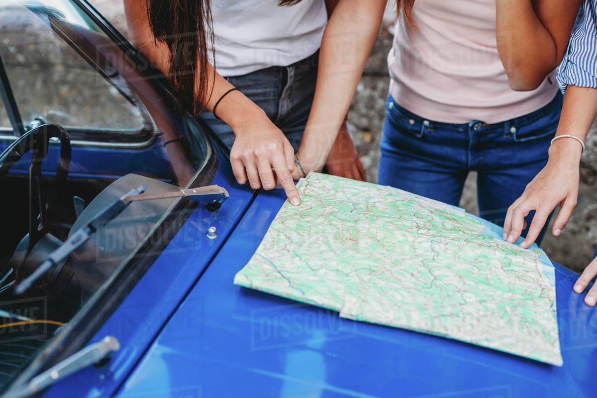 Friends reading route map on car bonnet - Royalty-free Stock Photo ...
