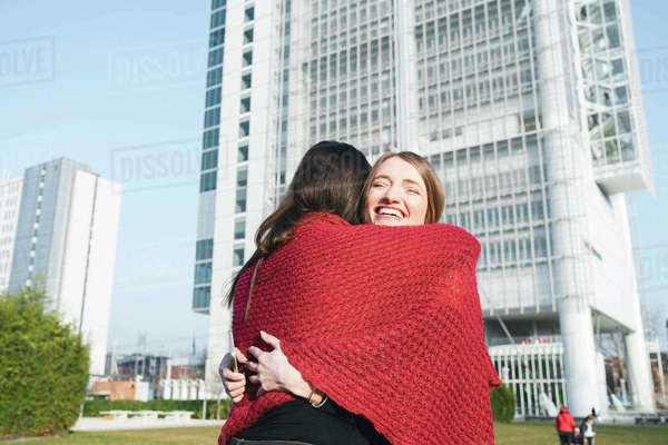 Two young women hugging outside skyscraper, Turin, Piemonte, Italy ...