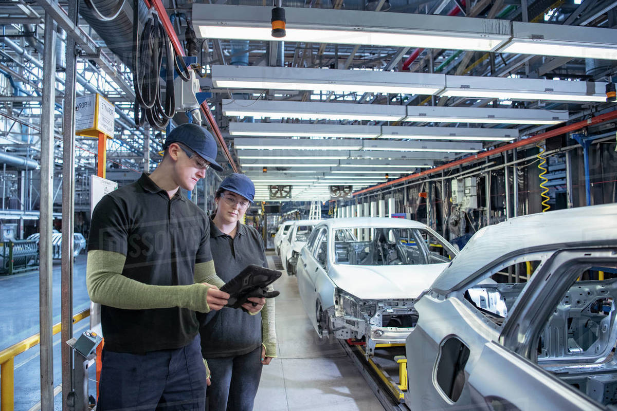 Apprentices inspecting cars on production line in car factory - Stock ...