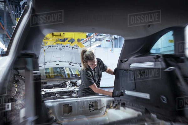 Female worker assembling car interior on production line in car factory ...