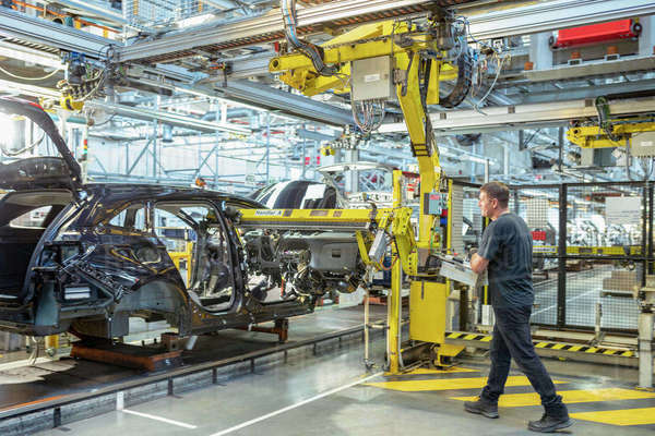 Worker inserting dashboard into car in car factory - Stock Photo - Dissolve