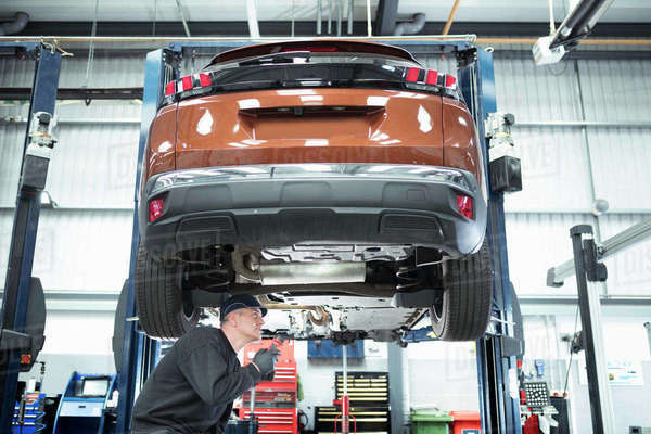 Engineer working under car on lift on car service centre - Stock Photo ...