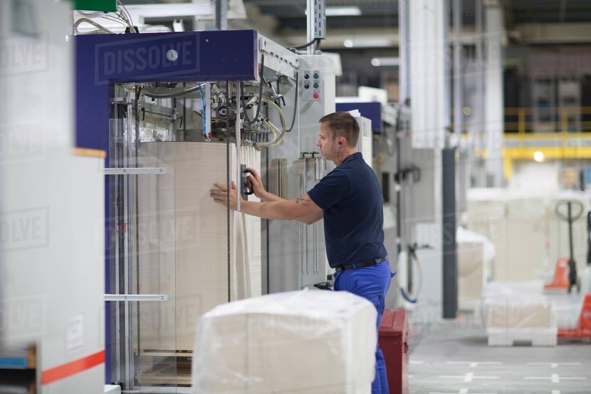 Worker using machine in paper packaging factory - Stock Photo - Dissolve