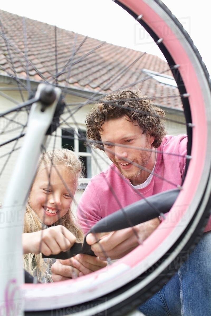 Father and daughter mending bike - Stock Photo - Dissolve