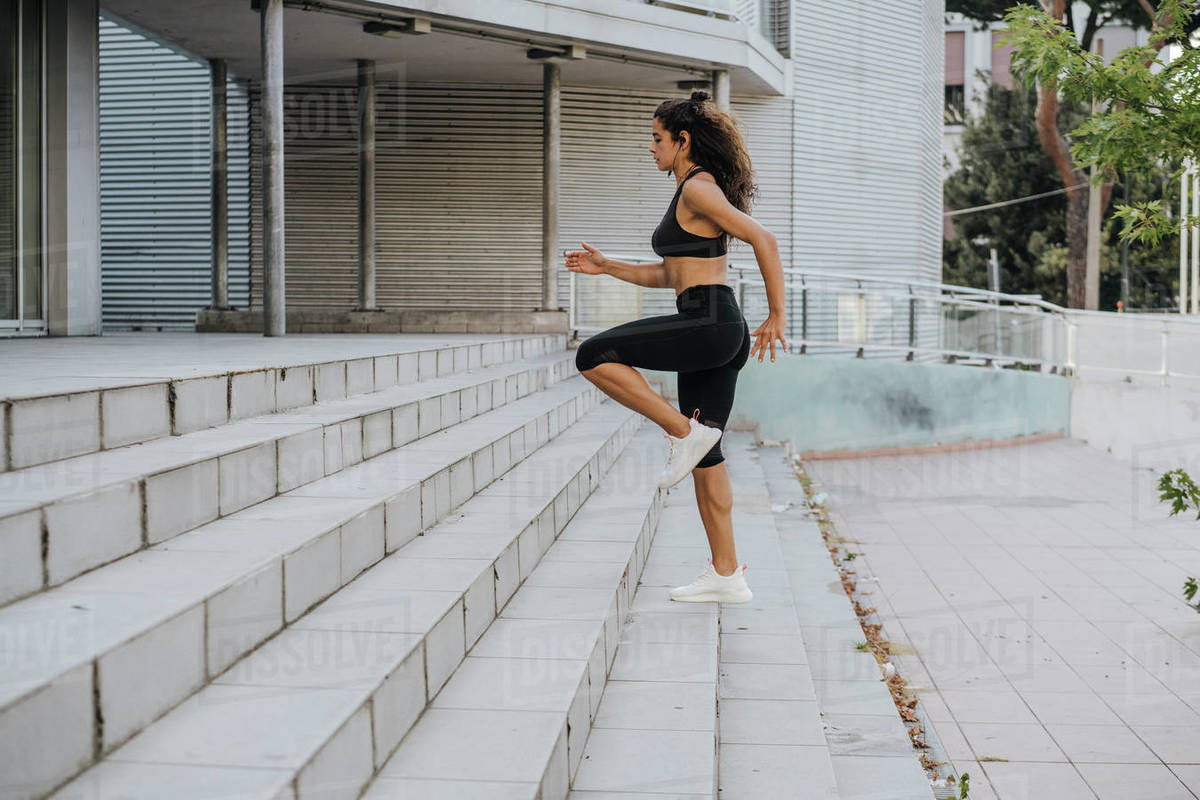Young woman jogging up steps - Stock Photo - Dissolve