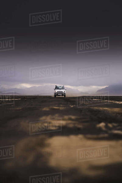 Off road vehicle on dirt track, black sky in background ...