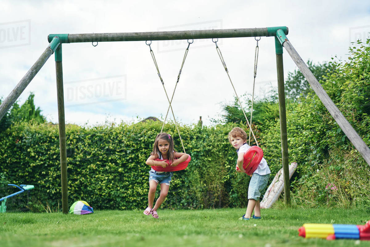 Girl and boy twisting around on swings in garden - Royalty-free Stock ...