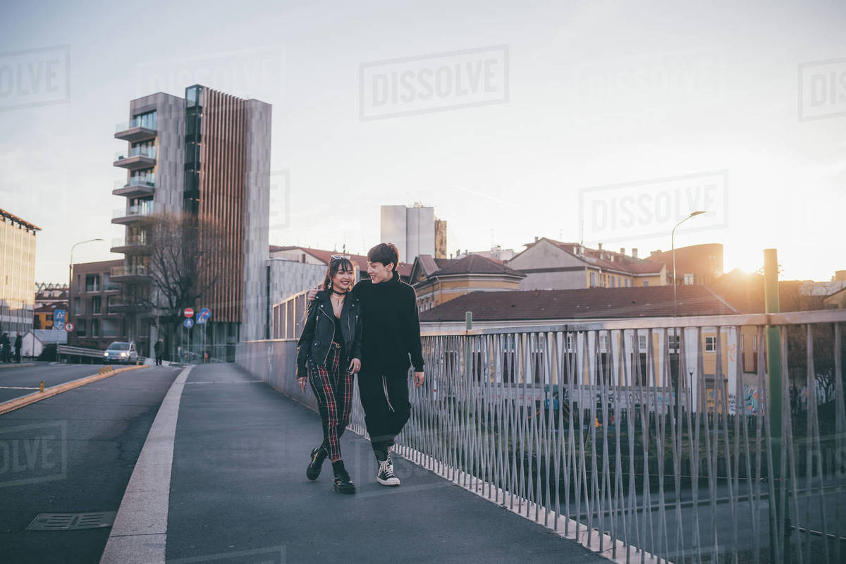 Trendy couple walking over bridge, Milan, Italy - Stock Photo - Dissolve