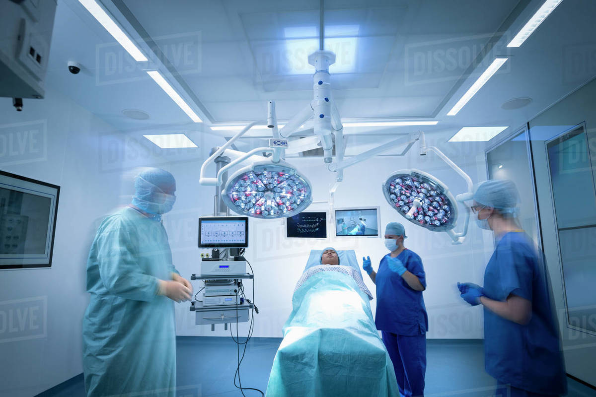 Nurses, surgeon and patient in operating theatre in hospital setting ...