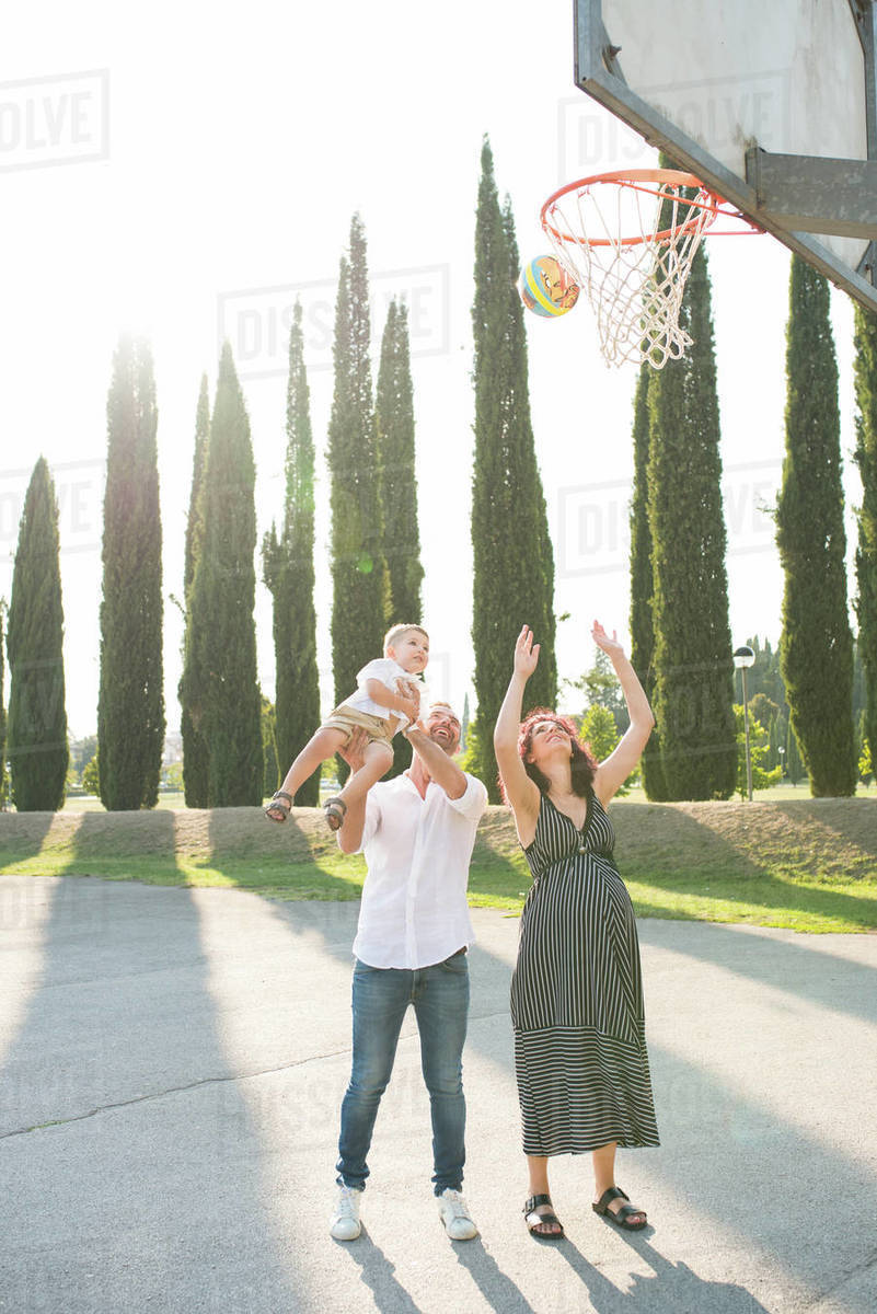 Parents with son playing netball in park - Stock Photo - Dissolve