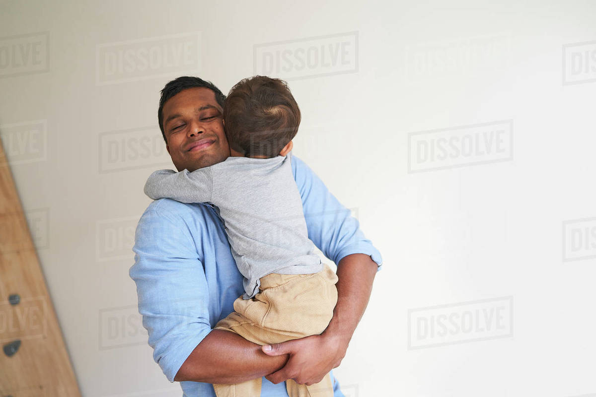 A man smiling, holding and hugging his son. - Stock Photo - Dissolve