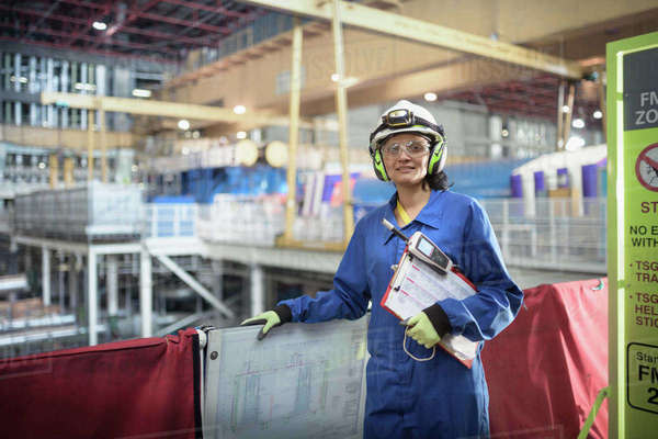Female engineer with a clipboard and electronic monitor at work in a ...