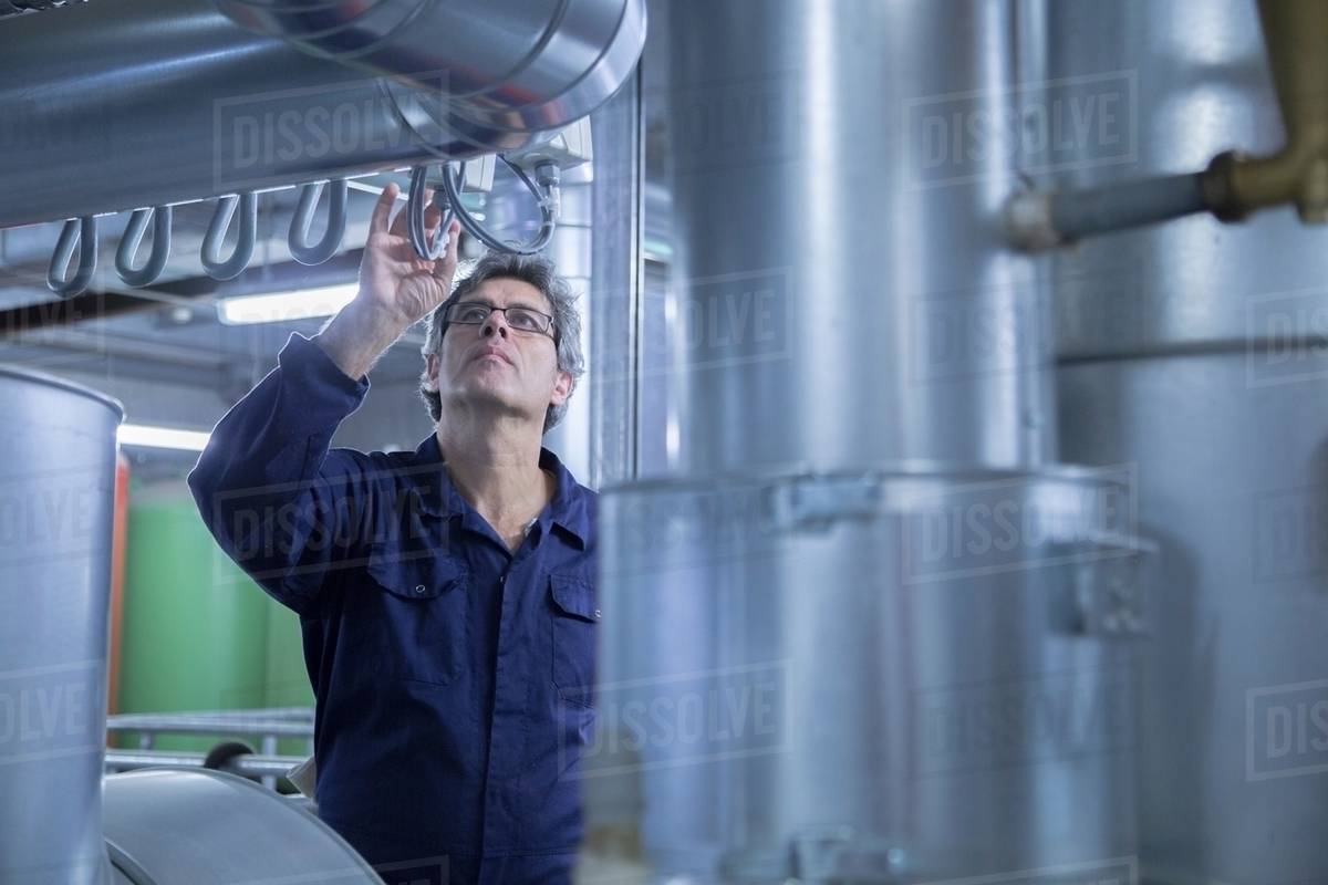 Engineer inspecting pipes in power station - Stock Photo - Dissolve