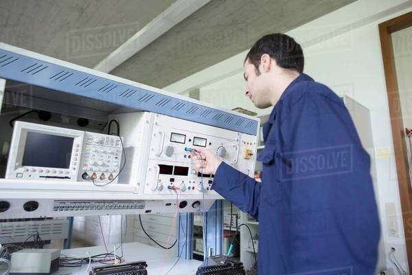 Male electrician testing control panel in workshop - Stock Photo - Dissolve