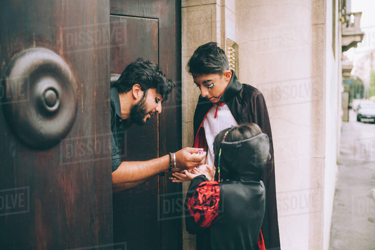 Man giving Halloween candy to children trick or treating - Stock Photo ...