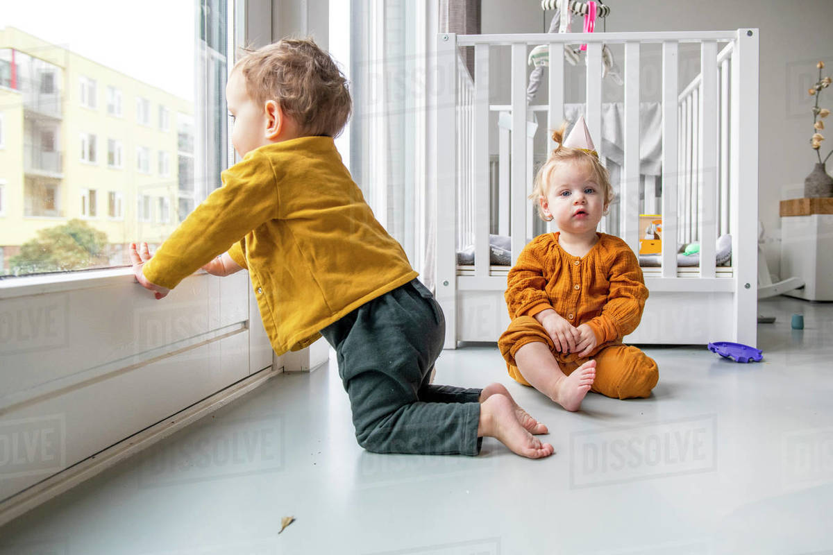 Two toddlers enjoying playtime by the window. - Stock Photo - Dissolve
