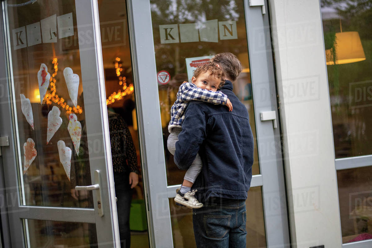 Adult carrying a child outside a building with lights - Royalty-free ...