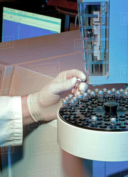 Scientist loading samples into an analytical machine in a laboratory ...