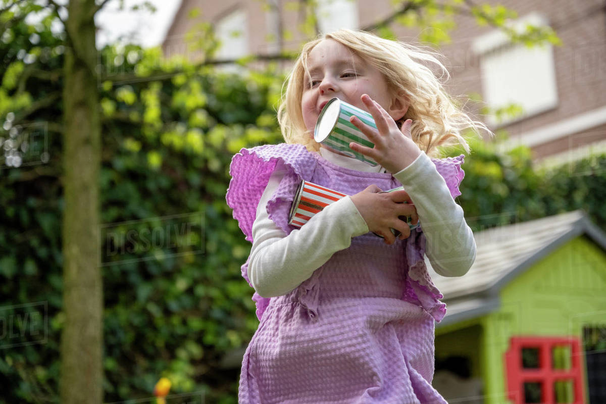 Two children are playing with colorful stacking cups on a grass lawn ...