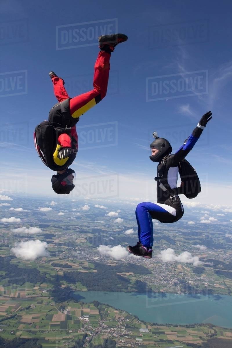 Team of two female skydivers in sit fly and head down positions over ...
