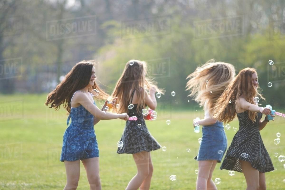 Four teenage girls spinning bubbles with bubble wand in park - Royalty ...