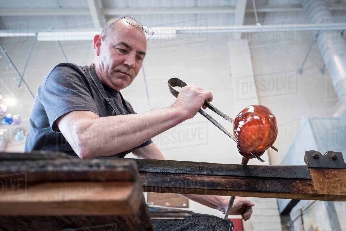 Glassblower forming molten glass - Stock Photo - Dissolve