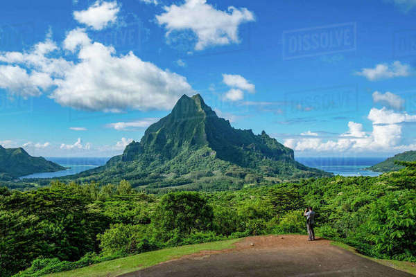 A person stands on a lookout point admiring the stunning view of a lush ...