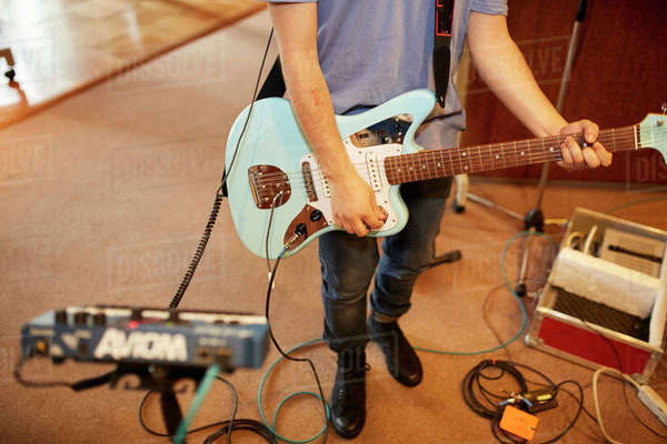A person standing while playing an electric guitar, surrounded by ...