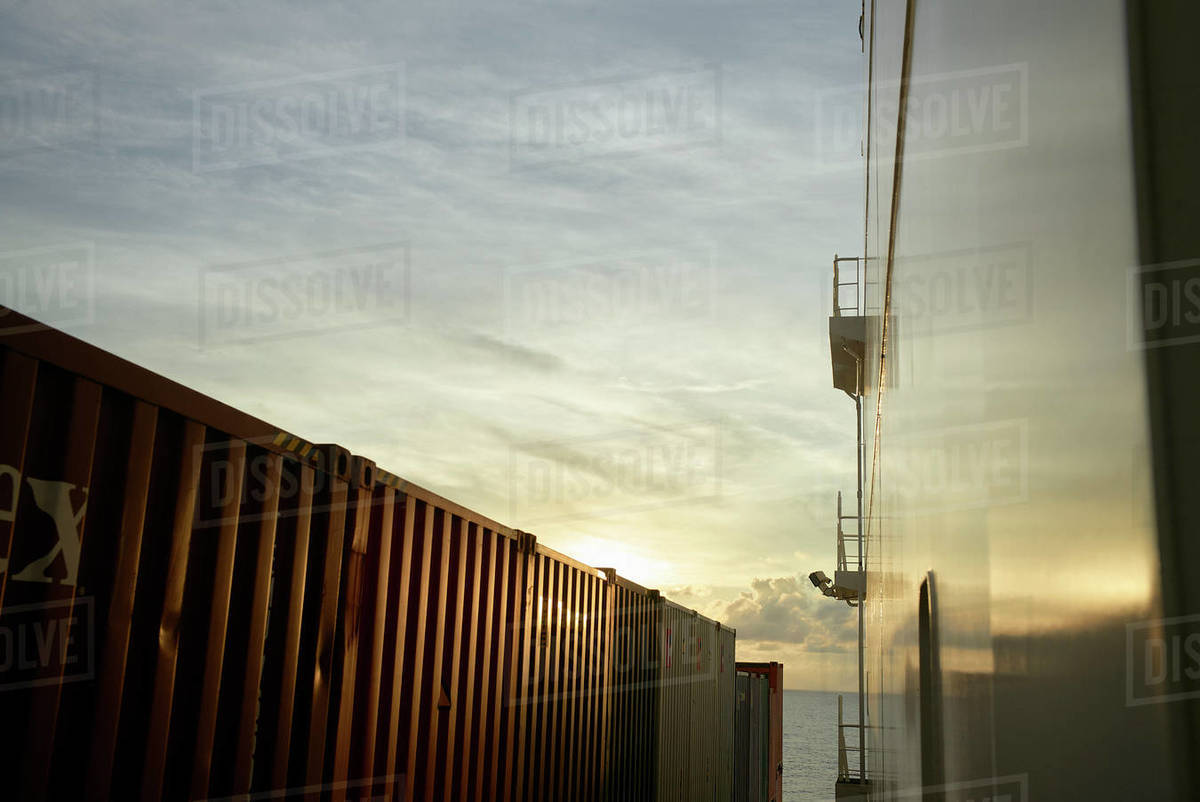 The image captures the side of a cargo ship with stacked shipping ...