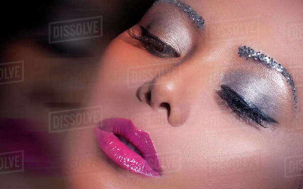 Close-up of a woman's face with detailed makeup, featuring silver ...