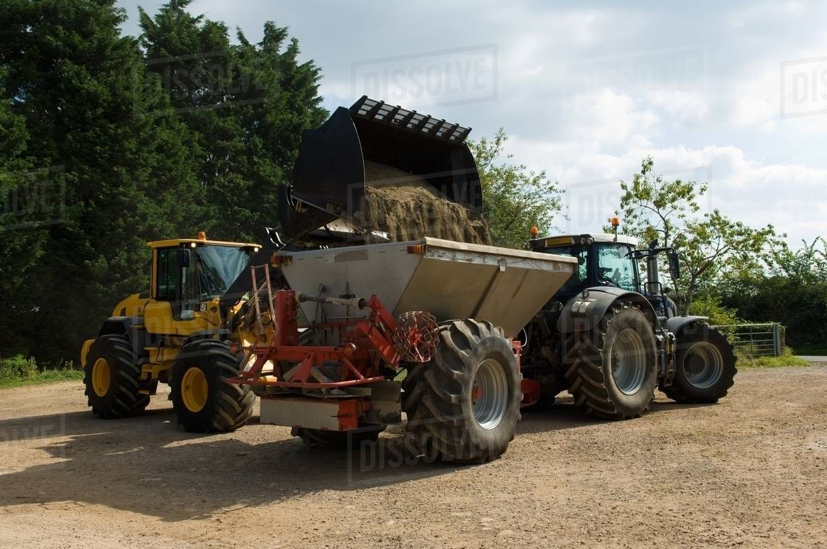 Farmer transferring organic fertilizer into fertilizer spreader in farm ...