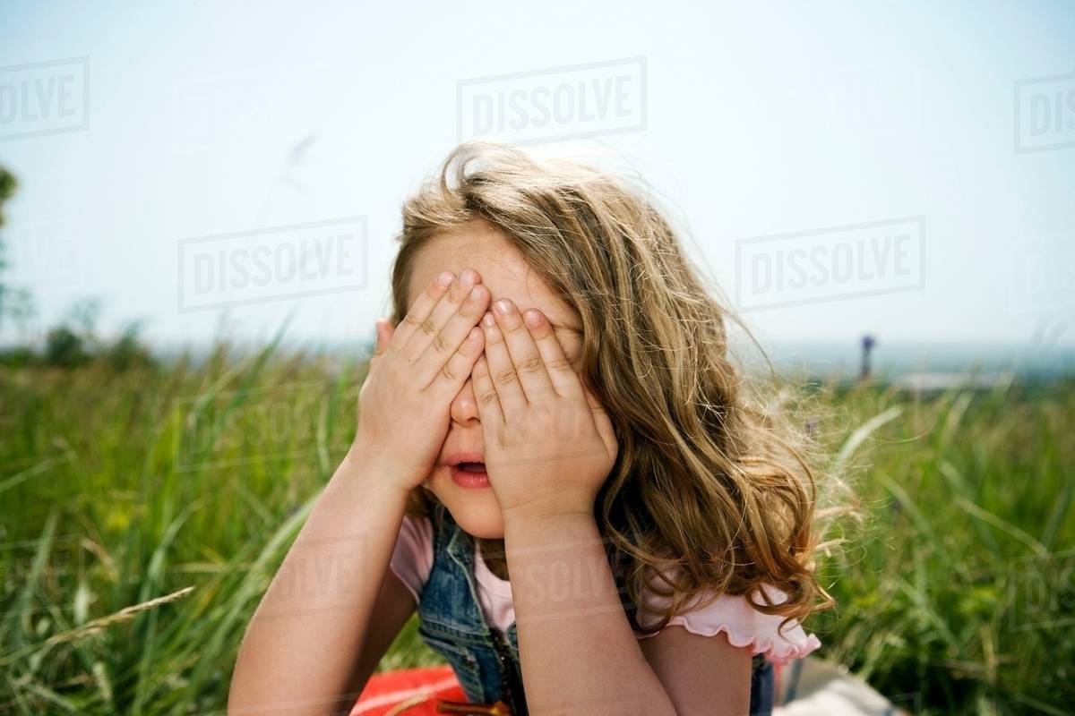 Girl hiding behind hands - Royalty-free Stock Photo | Dissolve